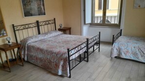 Um quarto com uma cama, uma mesa de cabeceira, uma janela e um quadro na parede.