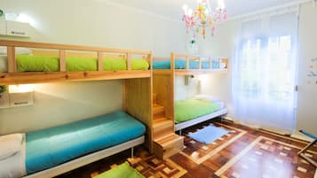 Um dormitório com beliches, escada de madeira, lustre e janela com cortinas.