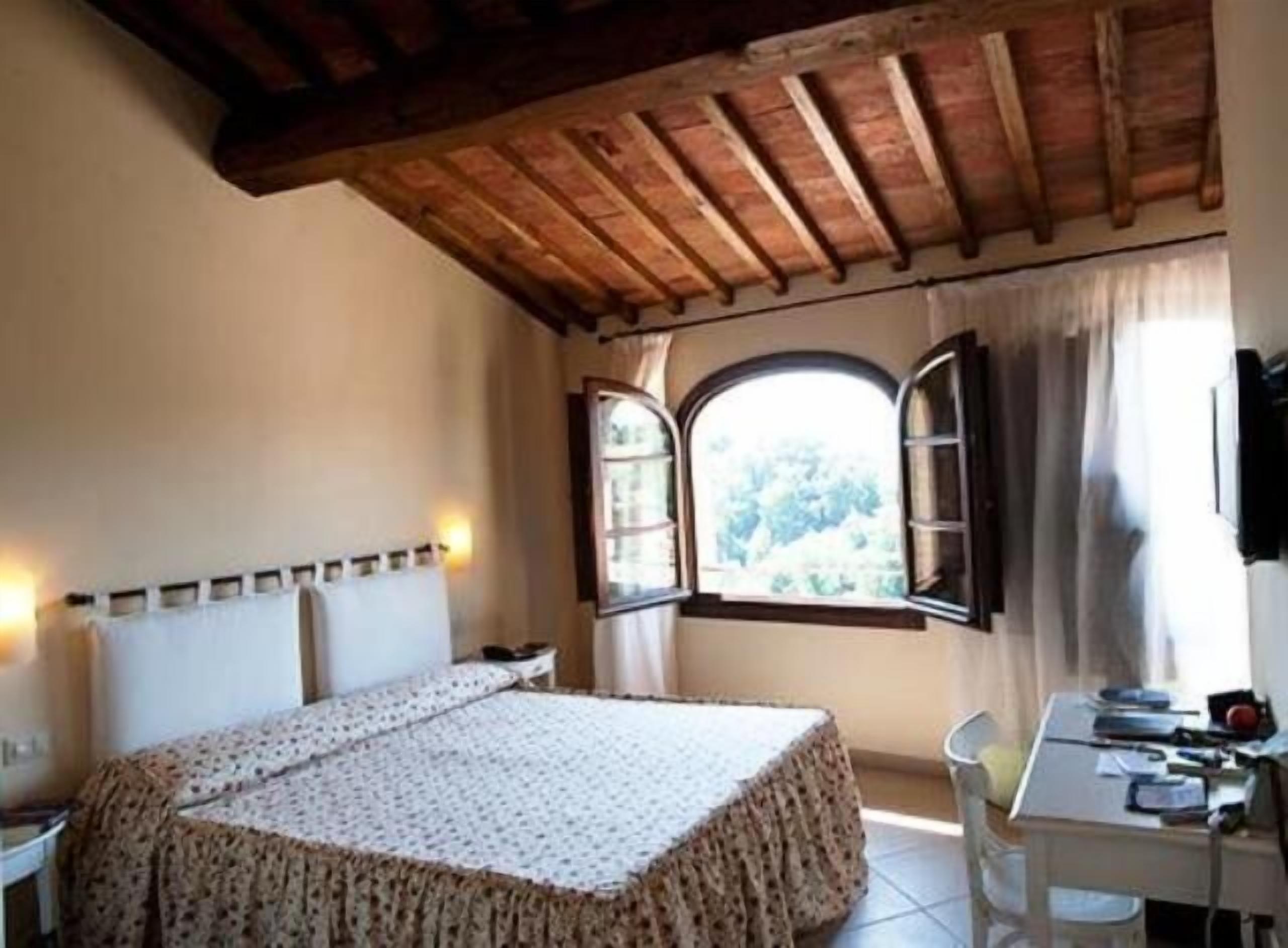 Um quarto com uma cama, uma escrivaninha e uma janela com cortinas.