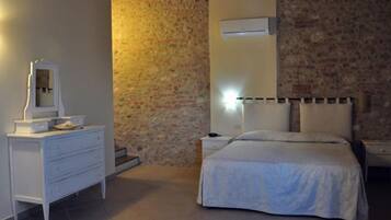 Um quarto com cama, cômoda, mesa de cabeceira e ar-condicionado na parede.
