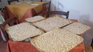Uma mesa de jantar com toalha xadrez e vários tabuleiros quadrados cheios de massa.