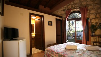 Quarto com cama, televisão, banheiro e vista para o exterior.