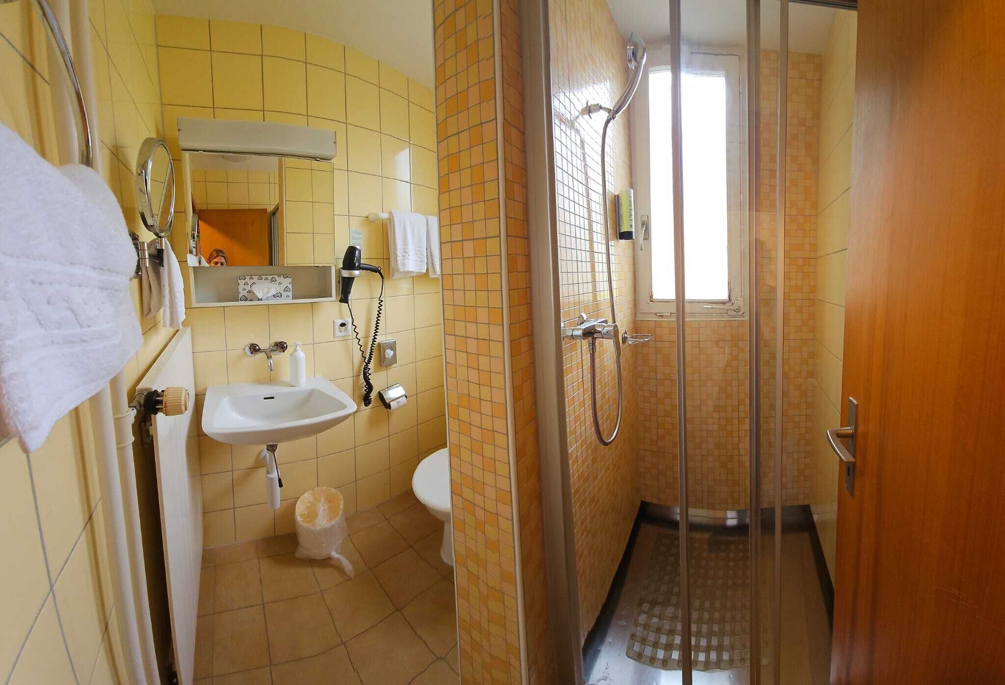 Casa de banho com lavatório, sanita e zona de duche.