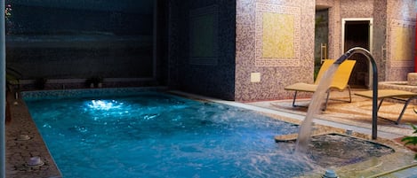 Uma área de spa com hidromassagem, um elemento aquático e um espaço de estar com uma cadeira e uma mesa.