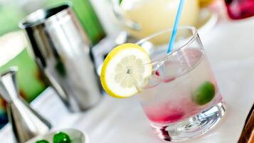 Um copo de cocktail com uma fatia de limão e um canudo azul, rodeado por shaker de cocktail e um jarro.