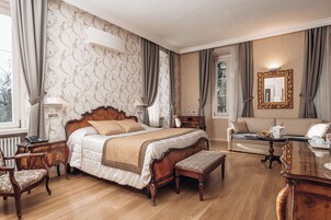 Um quarto espaçoso com uma cama grande, móveis de madeira, um sofá e uma mesa de jantar.