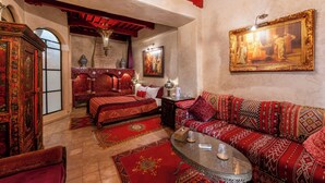 Quarto tradicional com sofá, duas camas, um candelabro e um quadro na parede.