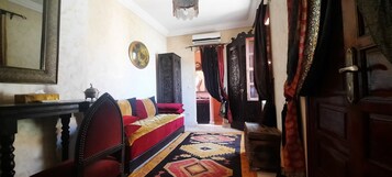 Quarto tradicional com sofá, um armário de madeira e um tapete estampado.