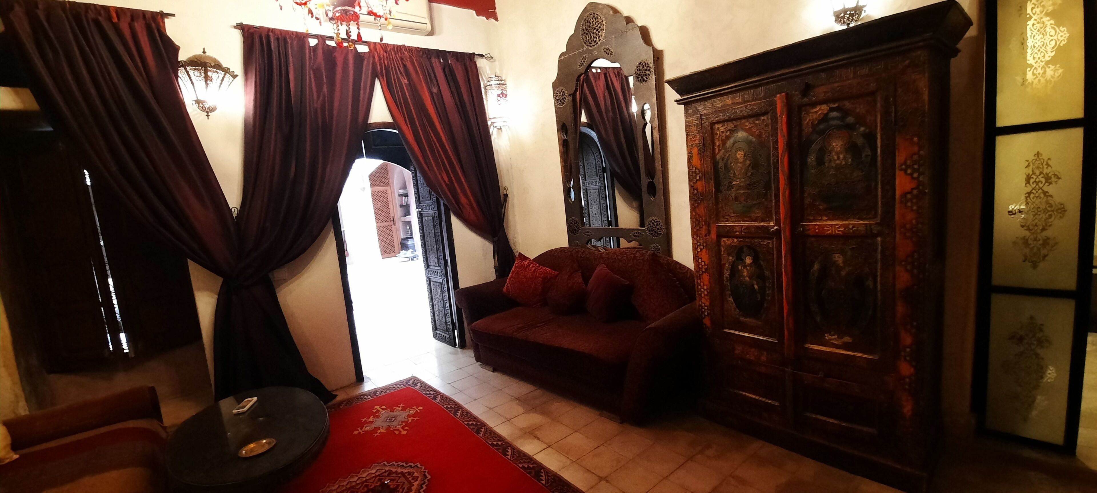 Quarto com sofá, armário de madeira e tapete vermelho.