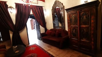 Quarto com sofá, armário de madeira e tapete vermelho.