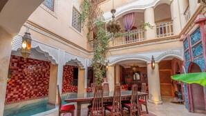 Um interior tradicional com área de refeições, piscina e detalhes arquitetônicos elaborados.