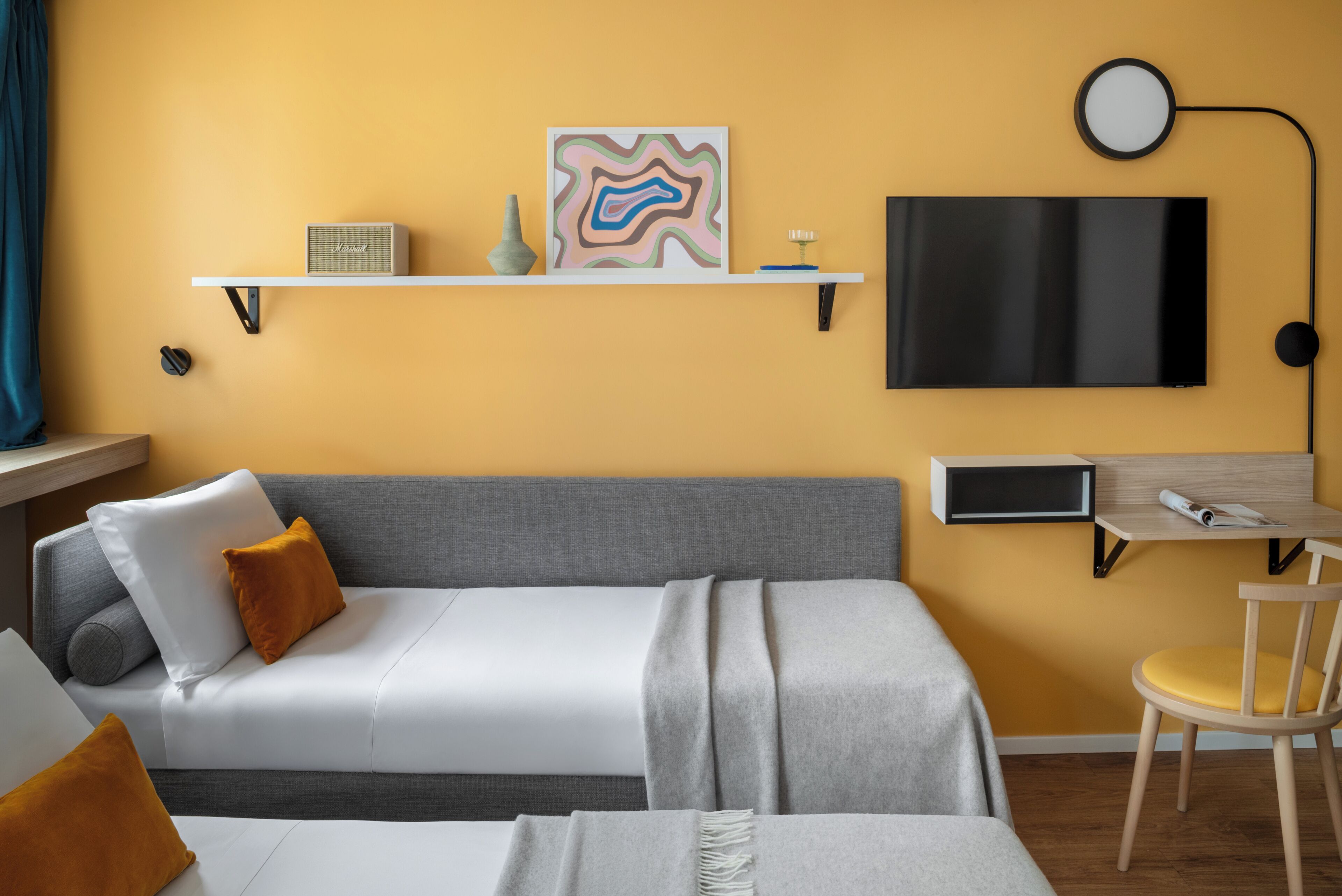 Quarto de hotel com duas camas, televisão, escrivaninha e uma cadeira.