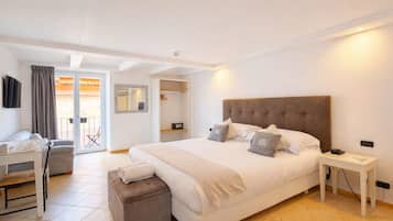 Quarto de hotel com uma cama grande, mesas de cabeceira, escrivaninha e uma cadeira.