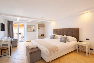 Quarto de hotel com uma cama grande, mesas de cabeceira, escrivaninha e uma cadeira.