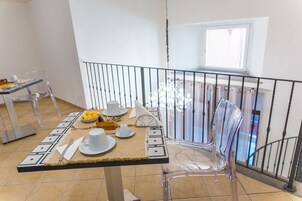 Uma área de refeições com uma mesa posta para dois, cadeiras transparentes e vista para a varanda.