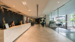 Uma área de recepção moderna com um balcão comprido, um posto de atendimento e um espaço de espera com cadeiras.