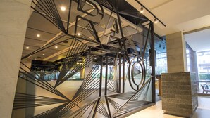 Um interior moderno com estruturas metálicas geométricas e um detalhe em pedra.