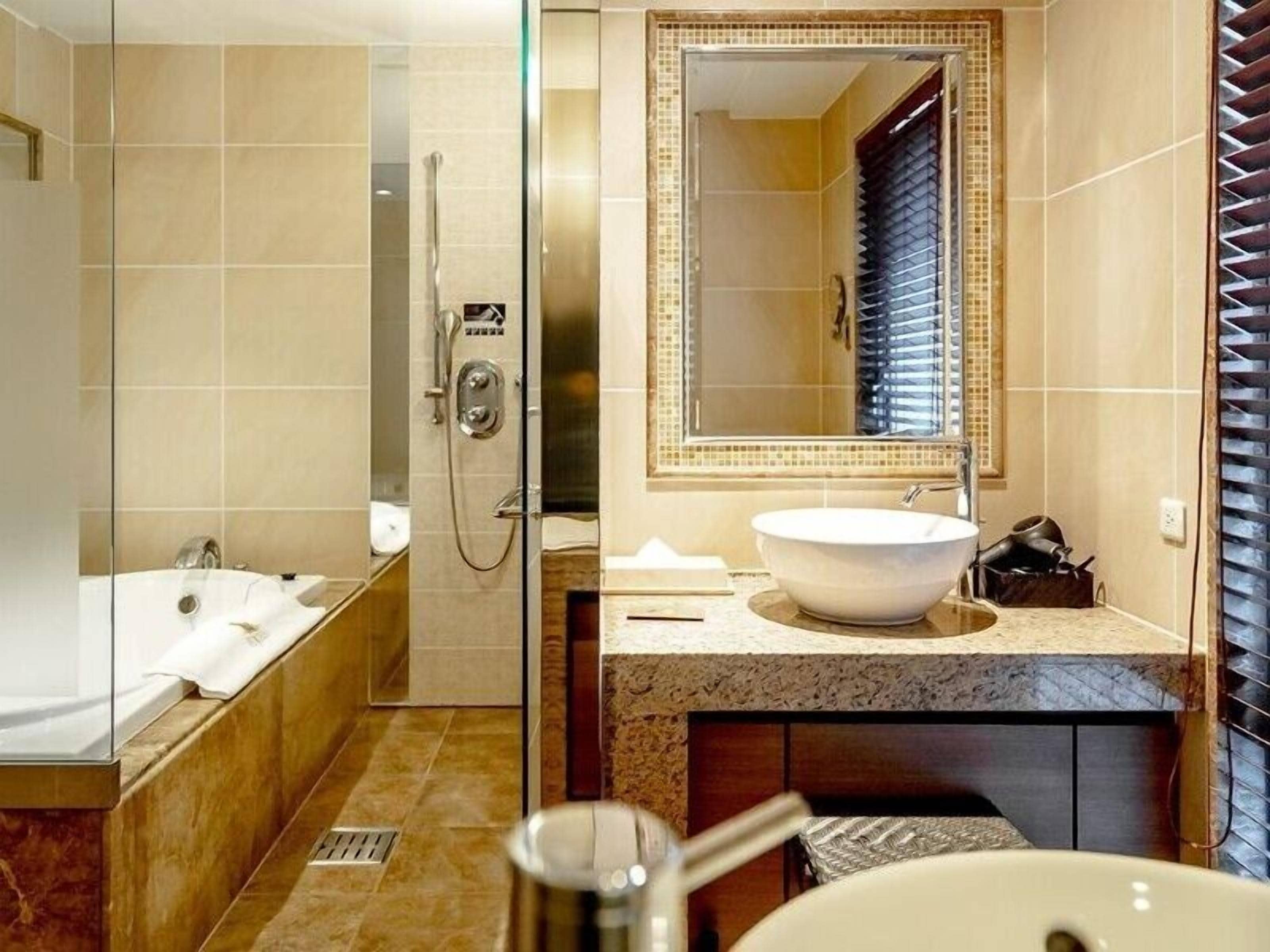 Uma casa de banho moderna com chuveiro amplo, uma banheira grande, toucador com lavatório e espelho sobre o lavatório.