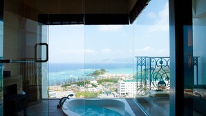 Uma varanda com porta de vidro, hidromassagem e vista para o oceano e edifícios.