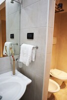 Um banheiro com pia, espelho, porta-toalhas e vaso sanitário.