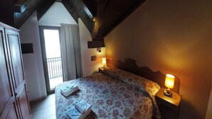 Quarto com uma cama, duas luminárias de cabeceira, uma janela com cortinas e uma porta.
