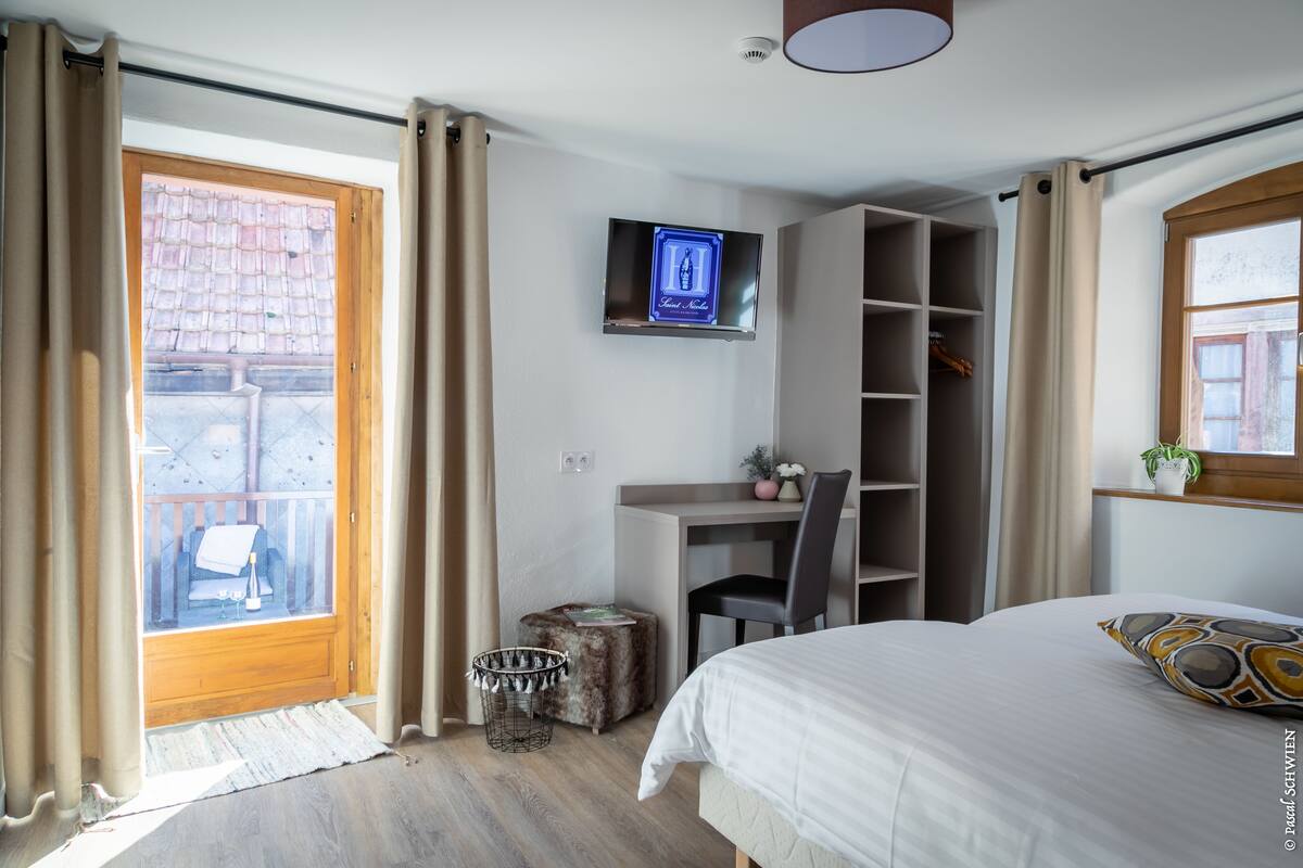 Quarto de hotel com cama, escrivaninha, televisão e vista para o exterior.