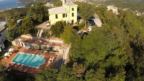 Um grande edifício com piscina e área de estar externa rodeado por árvores.
