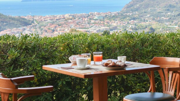 Mesa posta com itens de café da manhã e vista para uma cidade costeira.