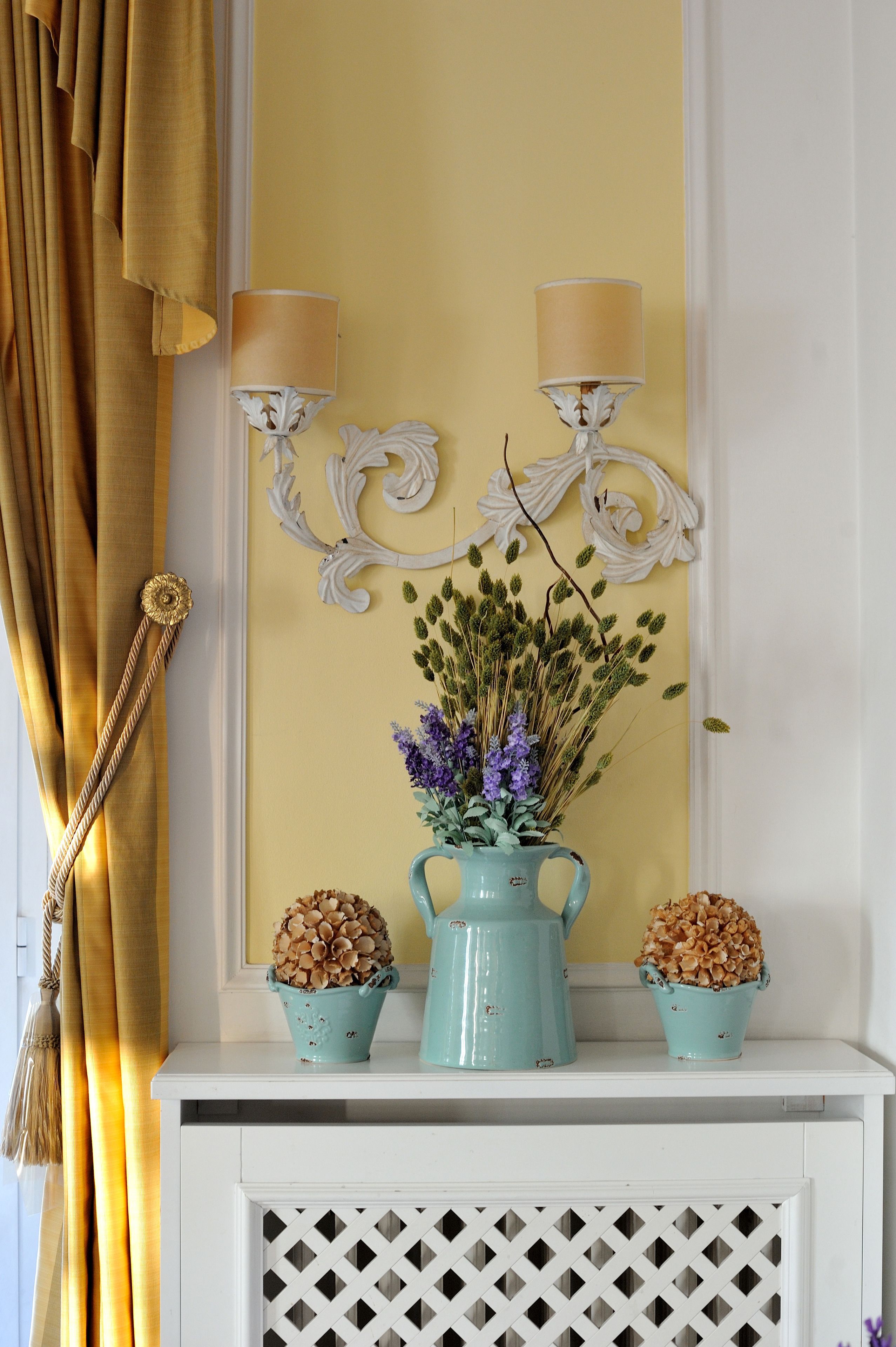 Um quarto com lareira branca, parede amarela e um objeto decorativo acima.