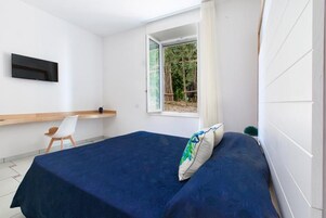 Quarto com cama, escrivaninha e janela.