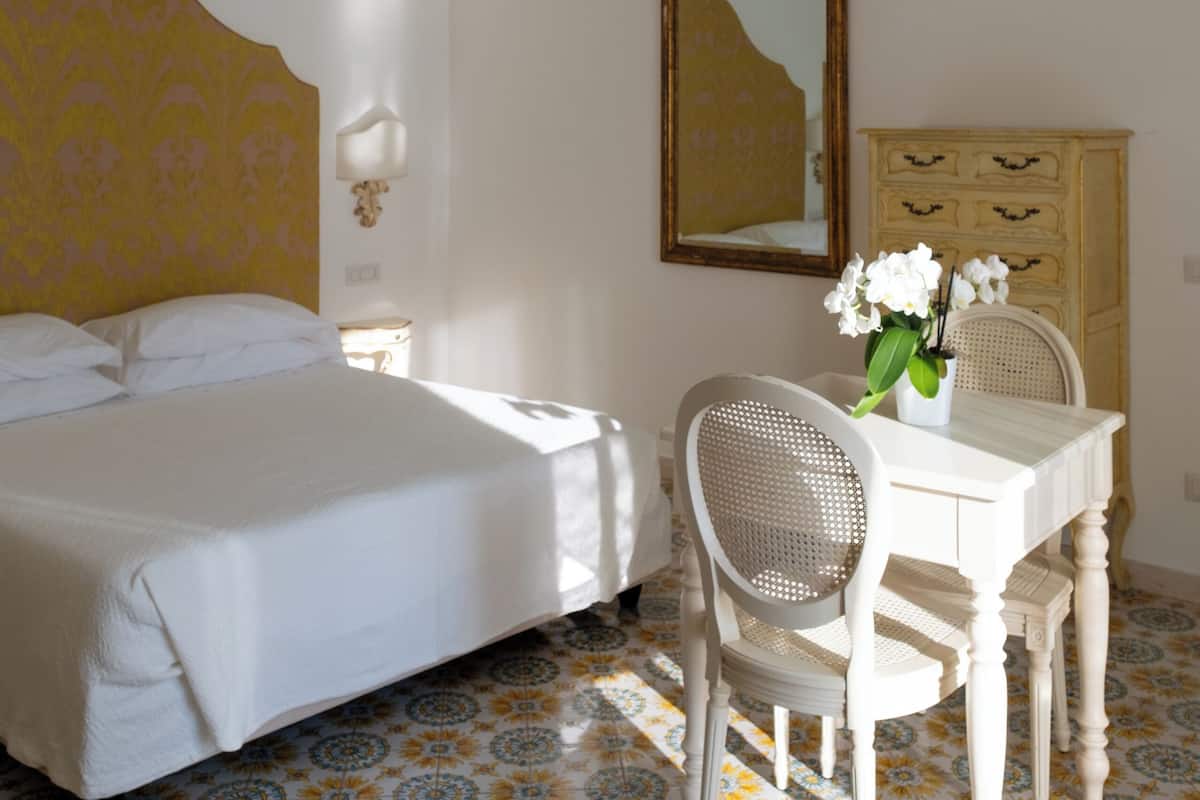 Um quarto com cama, uma mesa com cadeiras, um espelho e um armário.