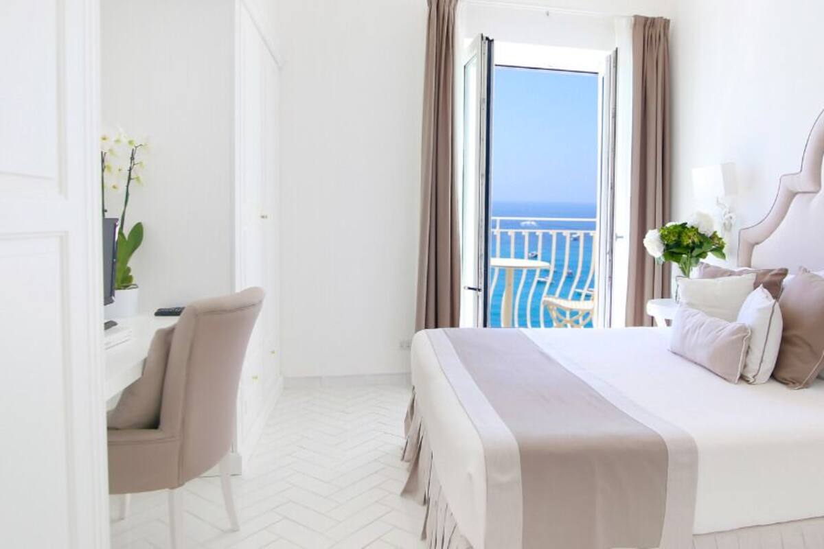 Quarto de hotel com uma cama grande, uma escrivaninha e vista para o oceano.