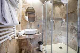 Um banheiro moderno com pia de mármore, chuveiro com box de vidro e porta-toalhas.
