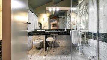 Uma casa de banho moderna com bidé, lavatório e cabine de duche em vidro.
