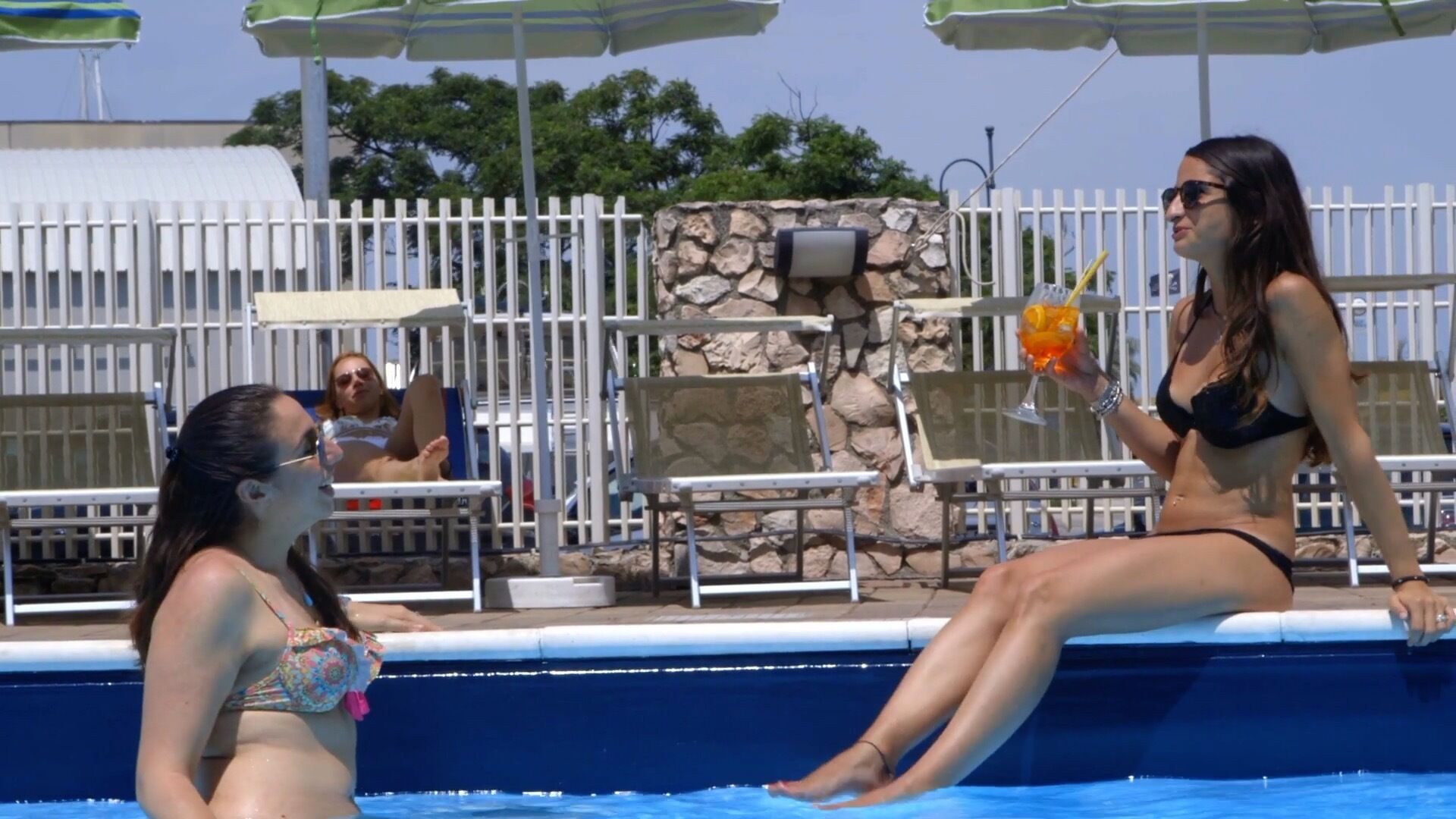 Uma área de piscina com espreguiçadeiras e guarda-sóis.