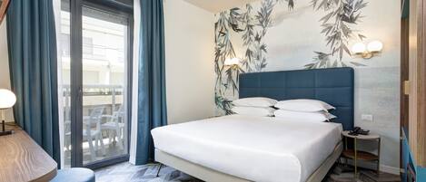 Quarto de hotel moderno com uma cama grande, um ventilador de teto, vista através de uma porta de vidro deslizante e uma parede com papel de parede de folhas de bambu.