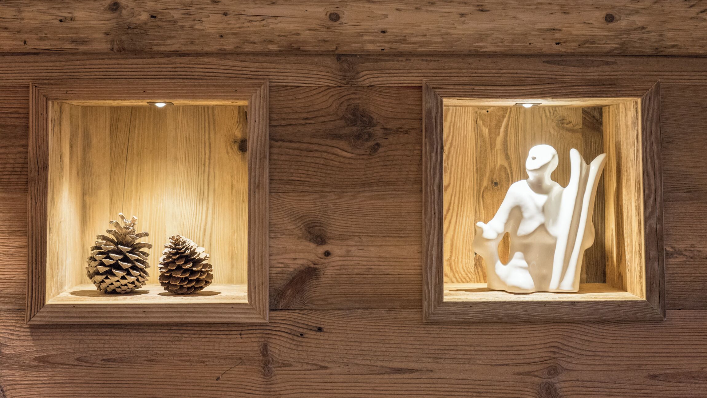 Duas vitrines de madeira com pinhas e uma escultura em cerâmica.