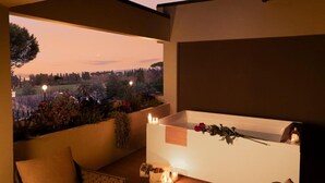Varanda com vista para um jardim e uma banheira com velas e uma rosa.