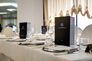 Mesa posta para refeição, com suporte de menu exibindo o logotipo do Hotel Cavalli Palace.