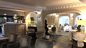 Um hall de hotel com área de bar, espaços para sentar e uma seção de refeições.