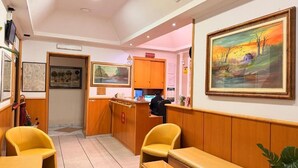 Um hall de hotel com painéis de madeira, um balcão de recepção e obras de arte nas paredes.