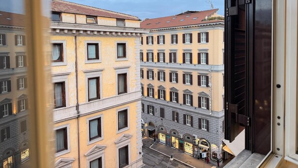 Vista de um hotel com vários andares e estilo arquitetônico clássico, apresentando grandes janelas e um pátio central.