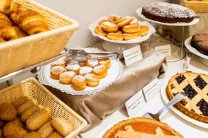 Buffet com diversos produtos de panificação, incluindo doces, donuts e tortas.