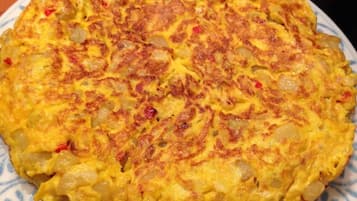Uma pessoa segurando um prato com uma omelete grande, redonda e dourada.