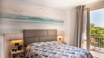Quarto de hotel com cama, mesas de cabeceira, um mural na parede e varanda com cadeira.