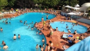 Uma grande piscina ao ar livre com várias pistas de natação e um deck ao redor.