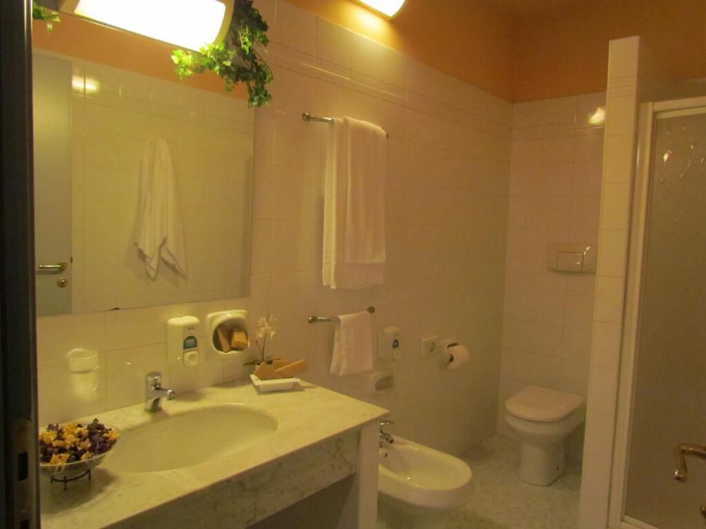 Uma casa de banho com lavatório, espelho, porta-toalhas, sanita e bidé.