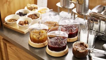 Buffet com diversos alimentos em recipientes transparentes, incluindo geleias e patês.