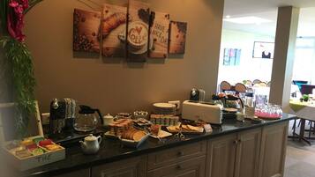 Buffet de café da manhã com diversos alimentos, um espaço para café e uma obra de arte com tema de café na parede.