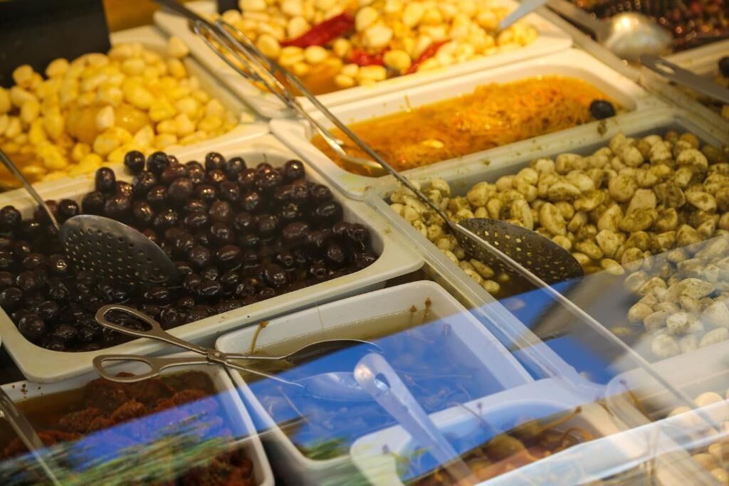 Uma apresentação de comida com diversos itens em recipientes separados, incluindo azeitonas, frutos secos e outros petiscos.